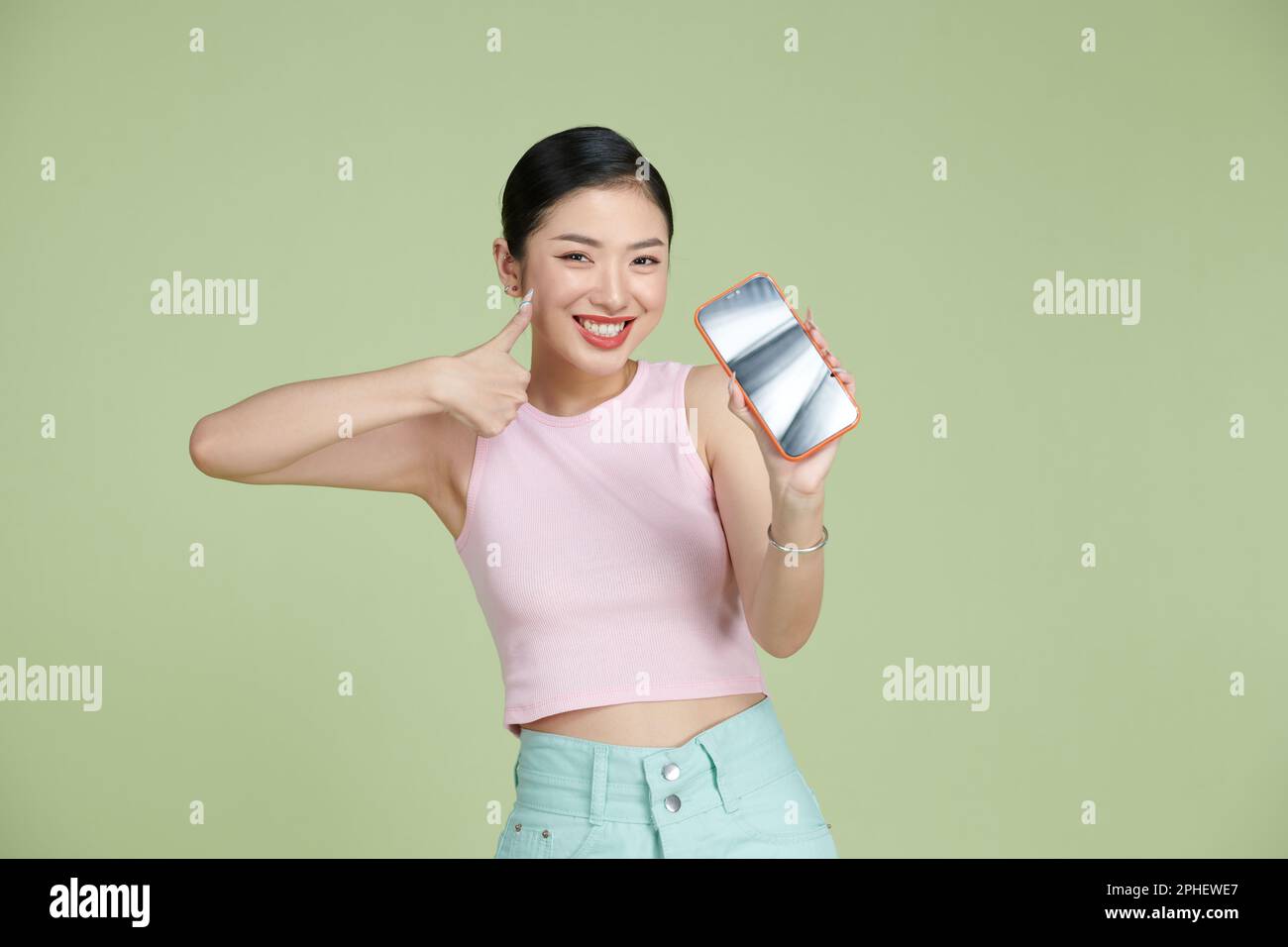 Portrait of smiling asian woman holding smartphone with black blank ...