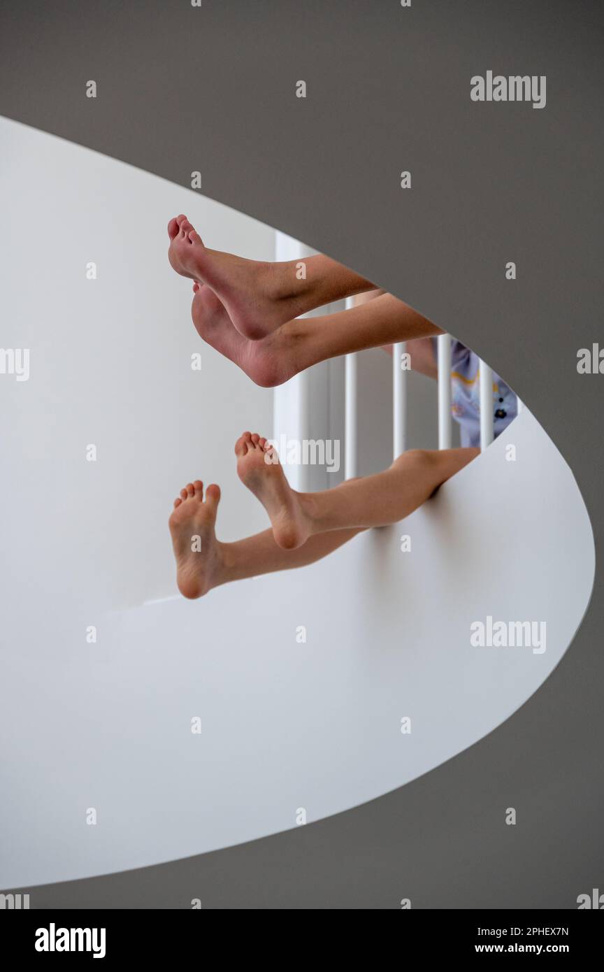 A childs legs hang over the edge of an indoor balcony Stock Photo - Alamy