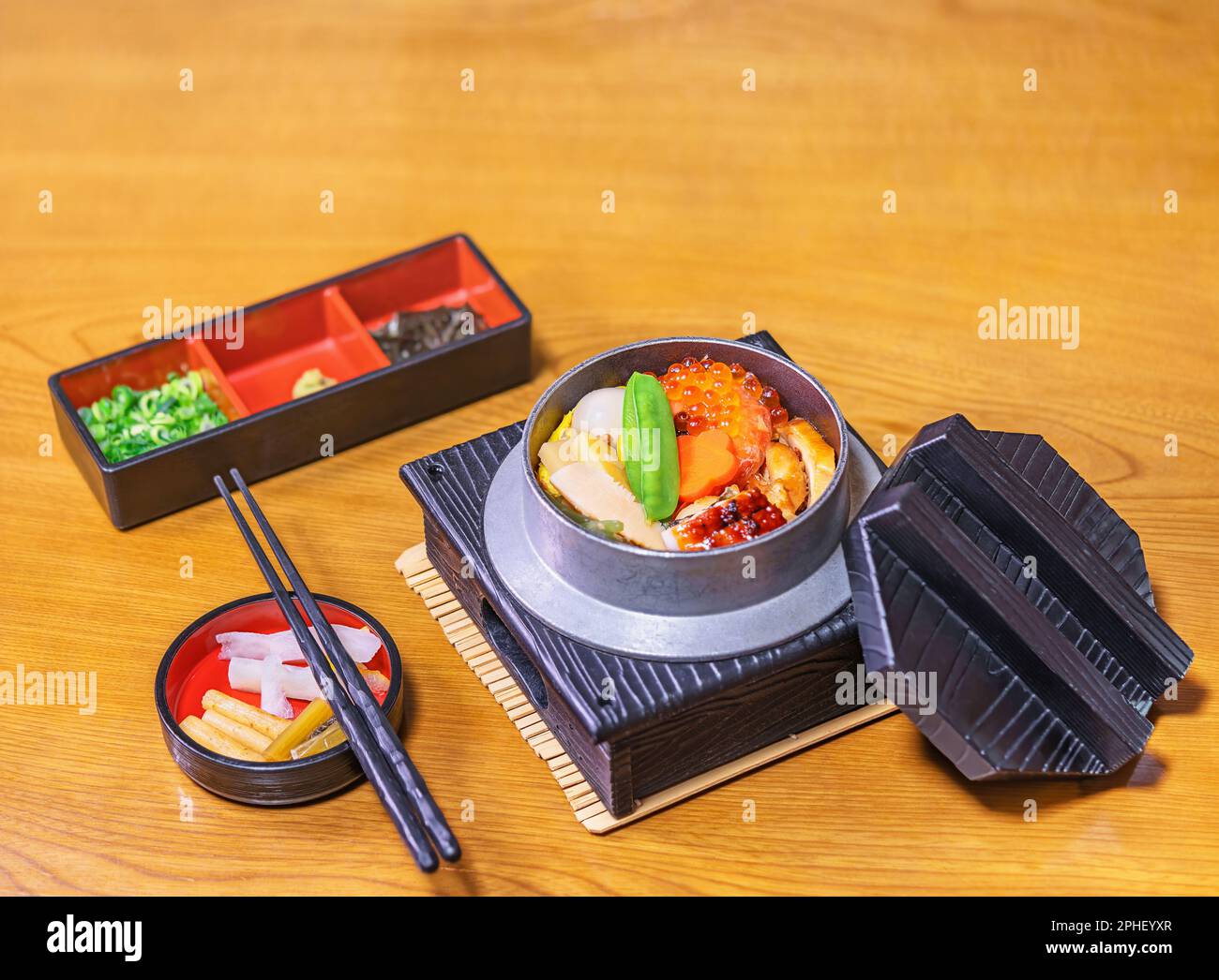 Japanese kamameshi rice dish cooked in an iron kama pot with ikura red caviar, edamame soybeans ...