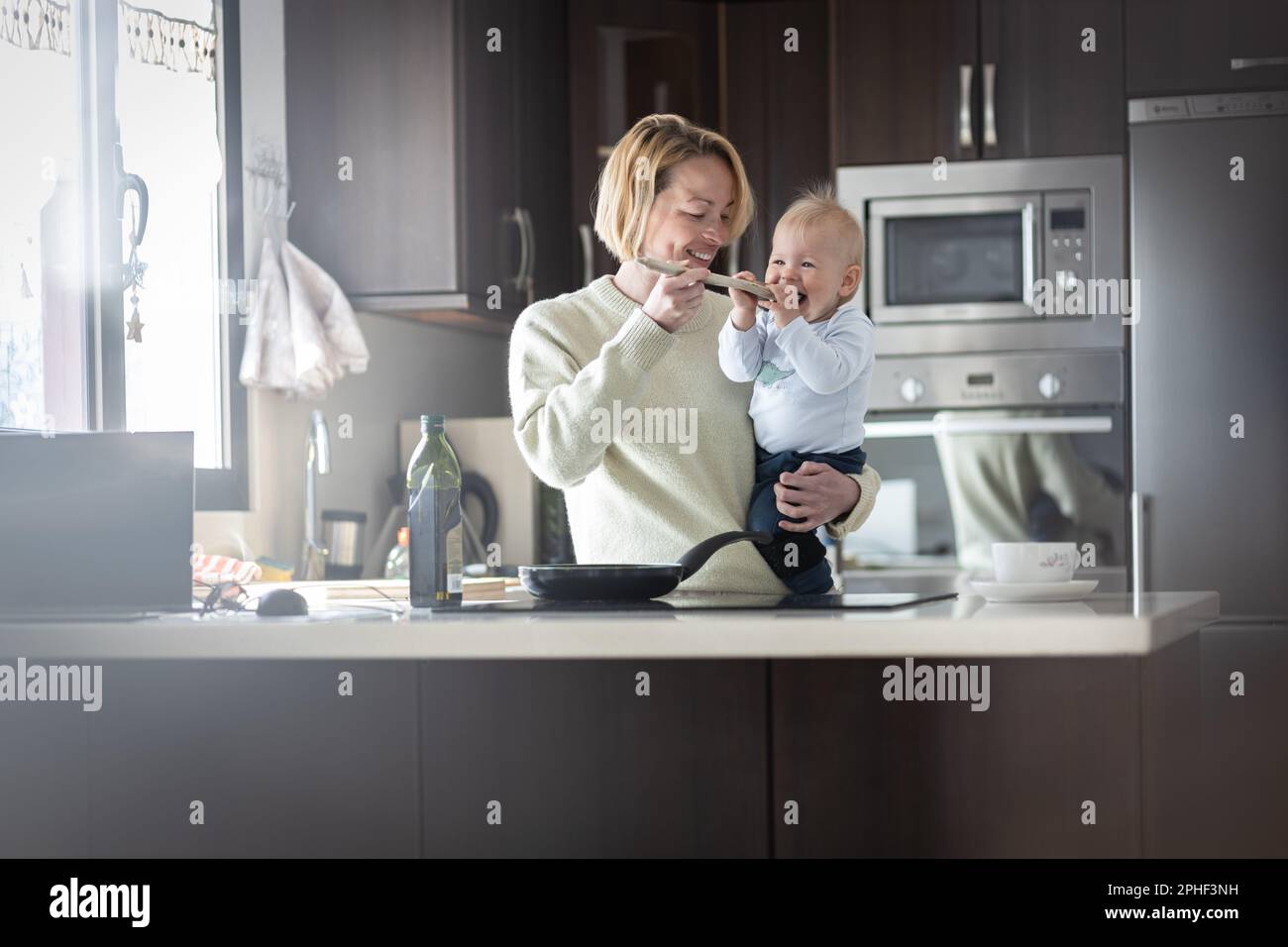 Happy mother and little infant baby boy cooking and tasting healthy ...