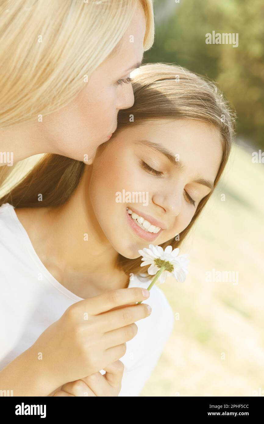 Caring mother kissing daughter, while resting in park Stock Photo - Alamy