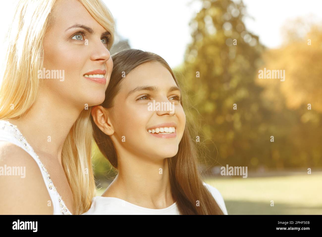 Smiling mother wit teenage daughter looking ahead in park Stock Photo ...
