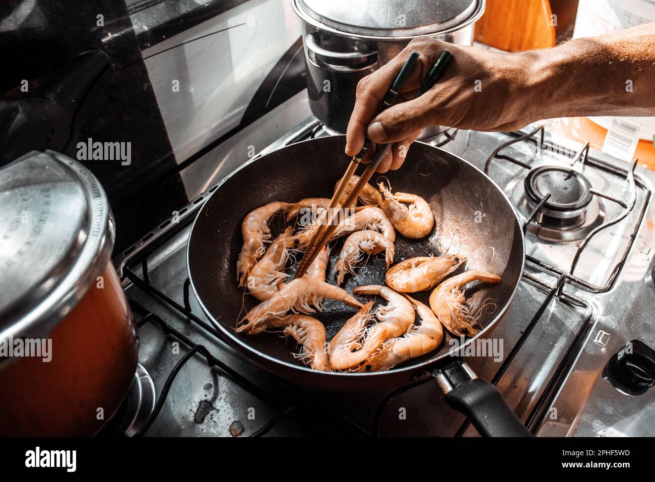 A chef is cooking prawns in a skillet on a gas stove top Stock Photo ...