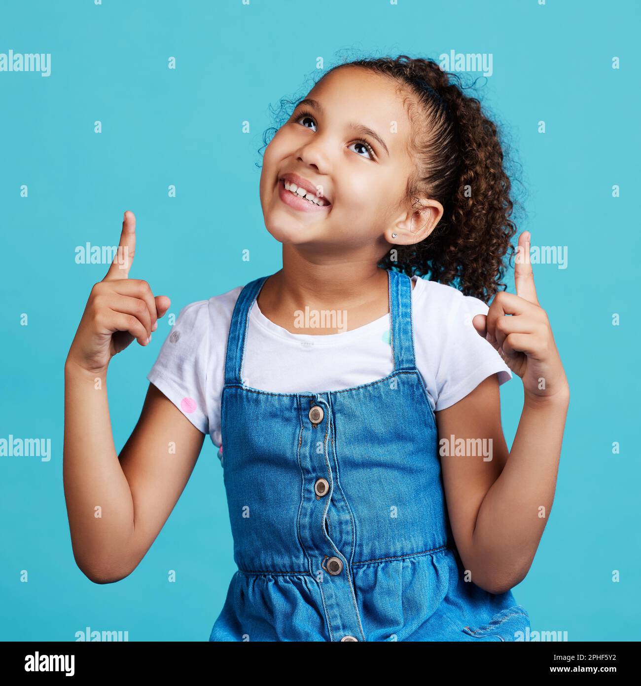 Happy, looking and a child pointing in a direction isolated on a blue ...