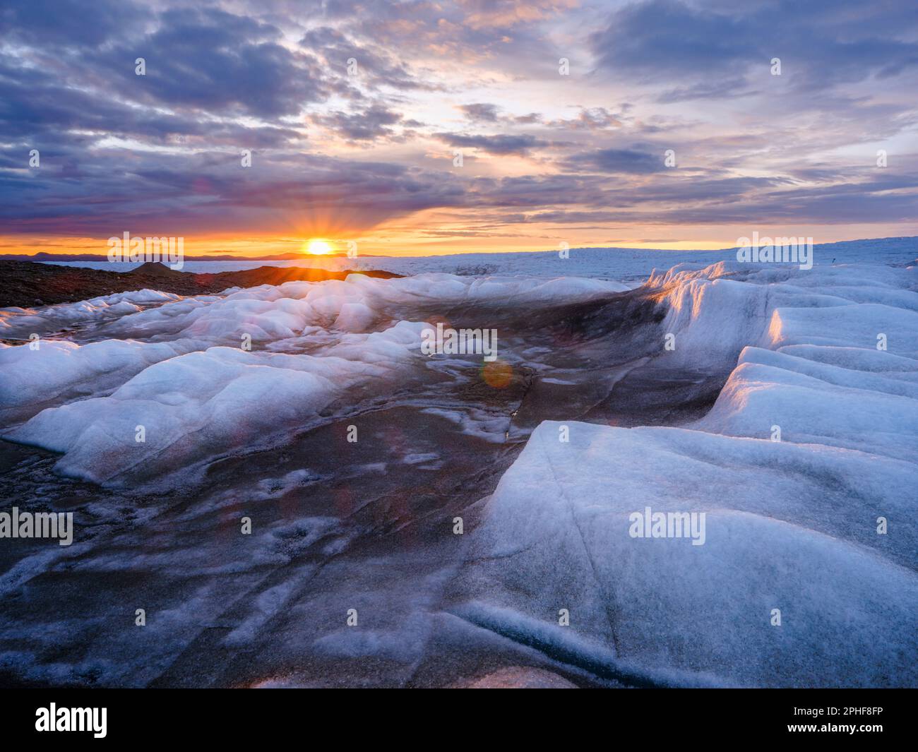 Midnight sun on the ice sheet. The brown sediment on the ice is created ...