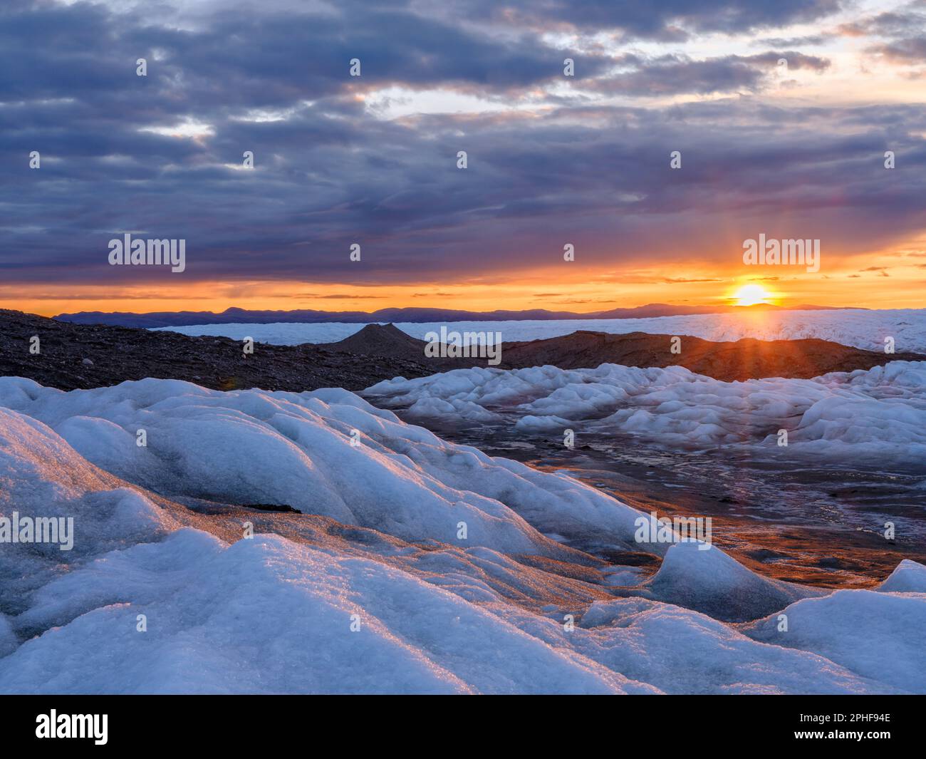 Midnight sun on the ice sheet. The brown sediment on the ice is created ...