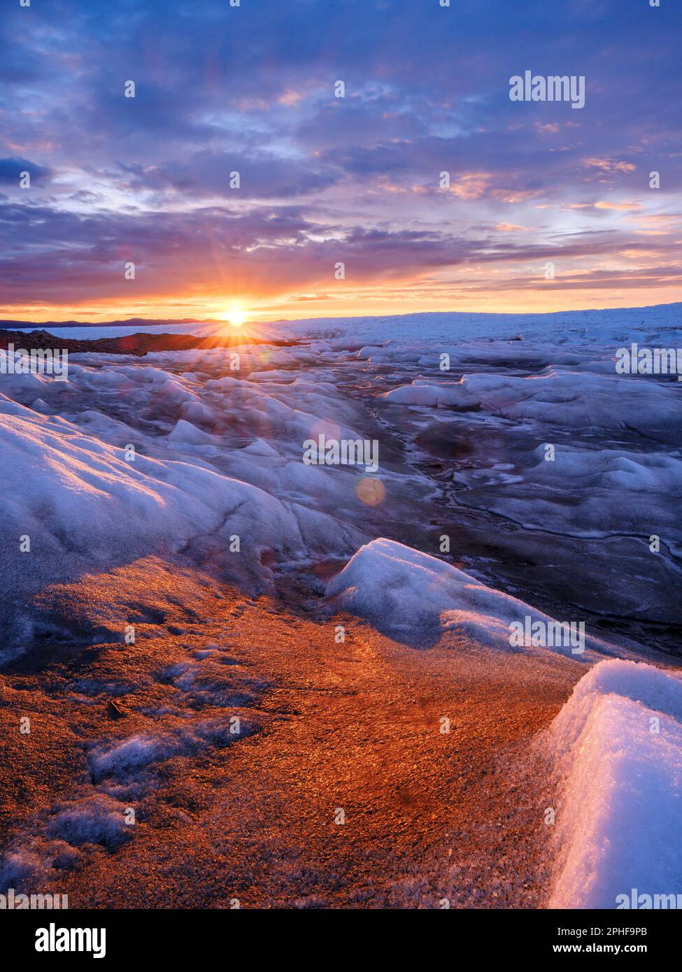 Midnight sun on the ice sheet. The brown sediment on the ice is created ...