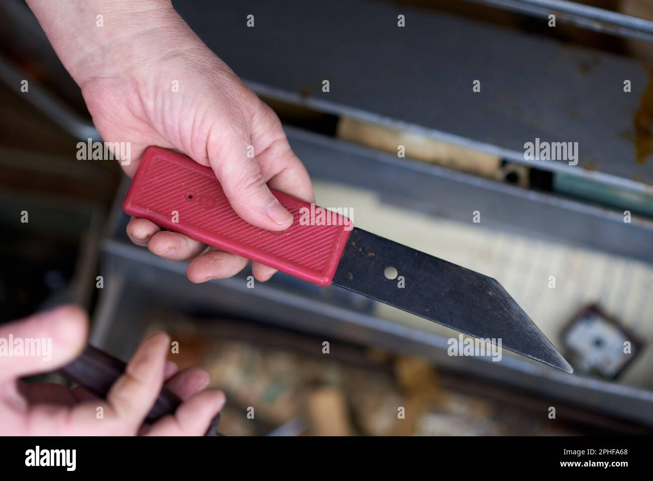 The master is holding a wallpaper knife with an oblique blade and a red ...