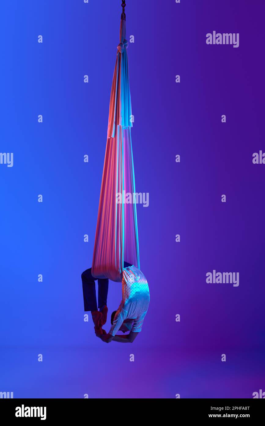 Young flexible man, professional aerial acrobat, gymnast training with ...