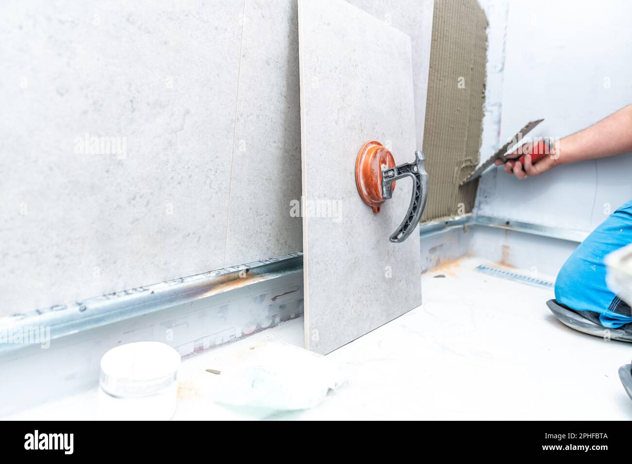 installation of large format tiles on the wall by a craftsman Stock ...