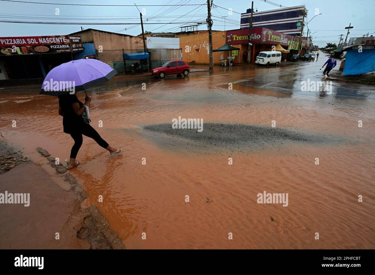 A resident crosses a street flooded by rain in the Sol Nascente favela ...