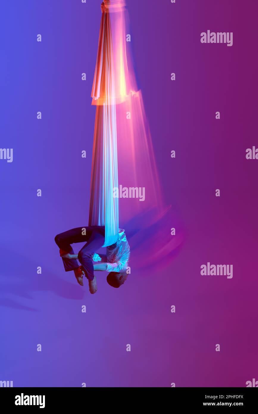 Young male professional aerial gymnast, acrobat training on aerial ...