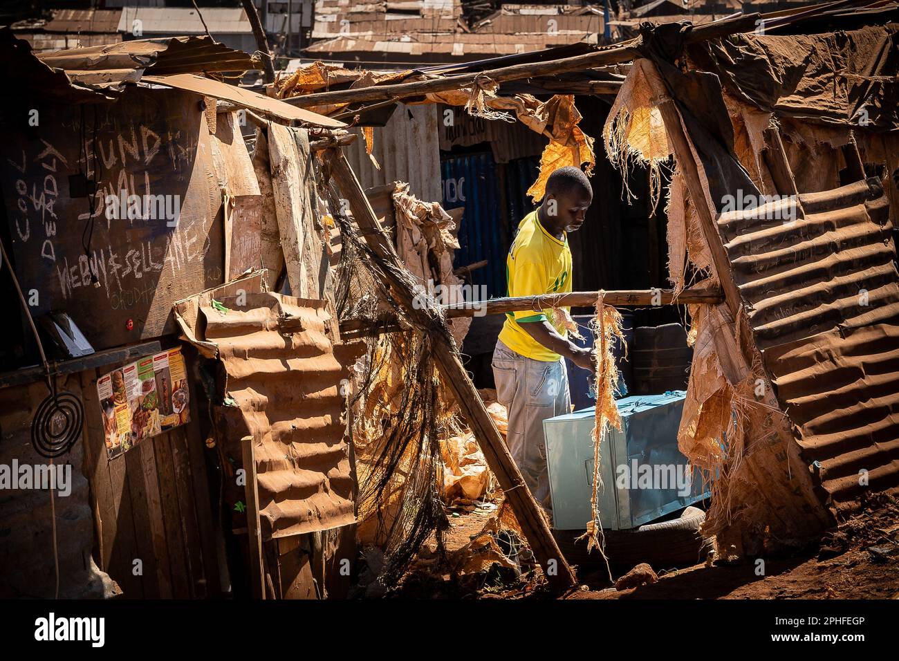 A man works inside a shack of Kibera slum, Nairobi, Kenya. Kibera is ...