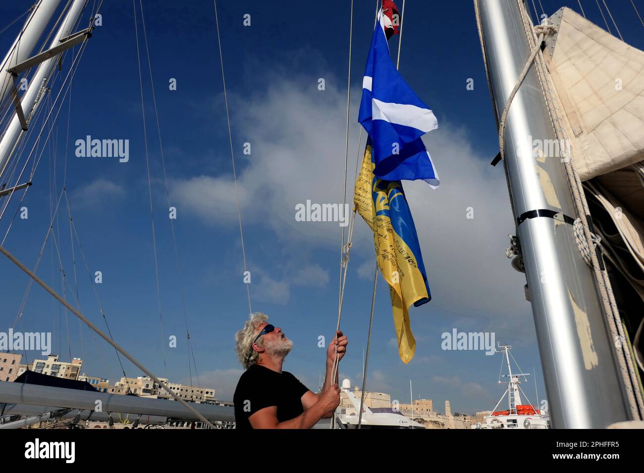 MEDITERRANEAN SEA - MARCH 24, 2023 - A man hoists a Ukrainian flag as ...