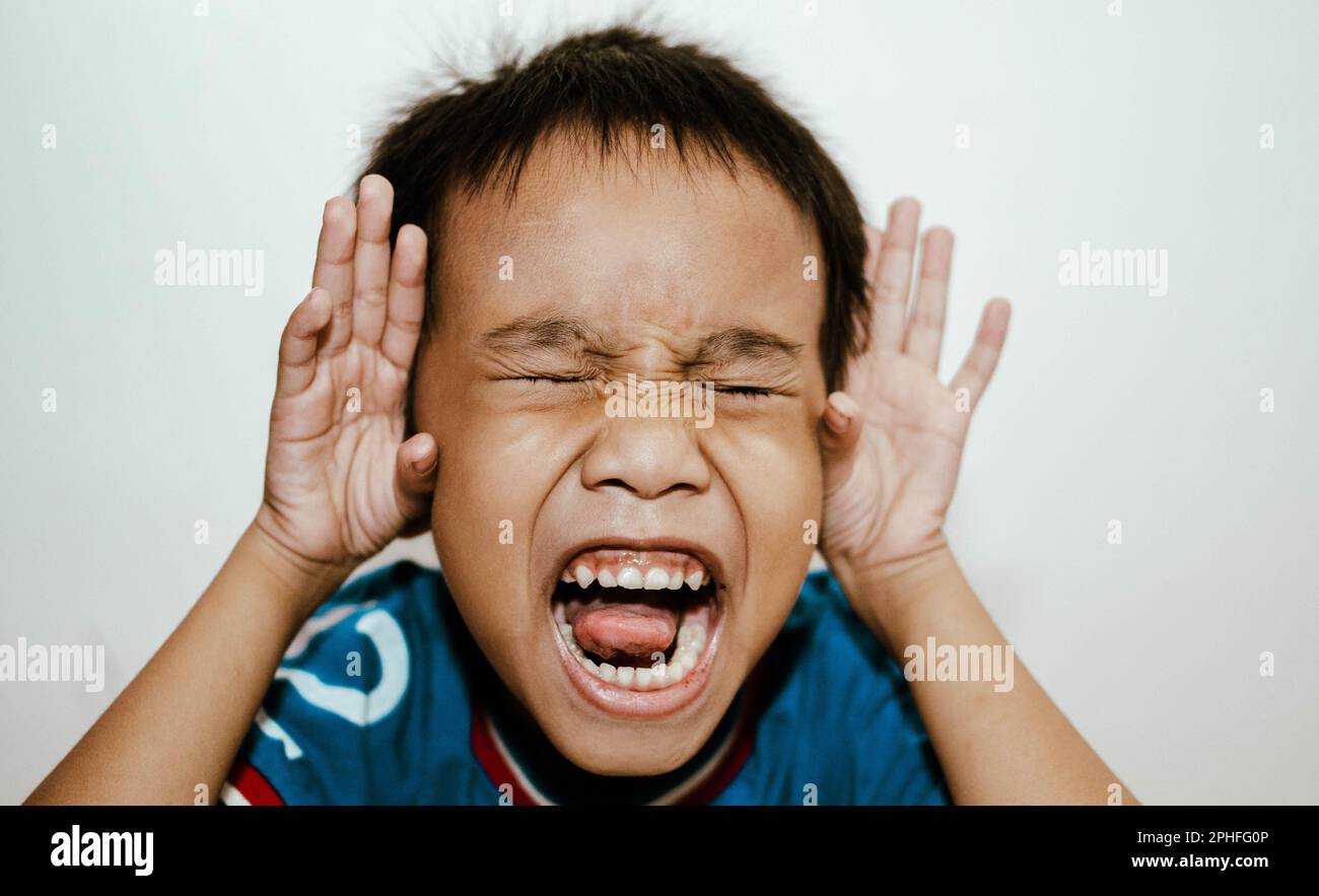 A young boy standing making a crazy funny face with hand gestures on a ...