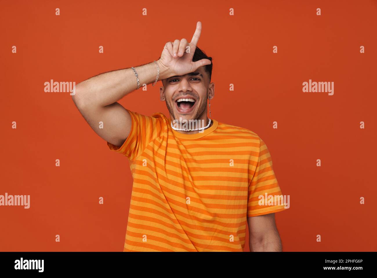 Young handsome stylish smiling man with opened mouth doing loser ...