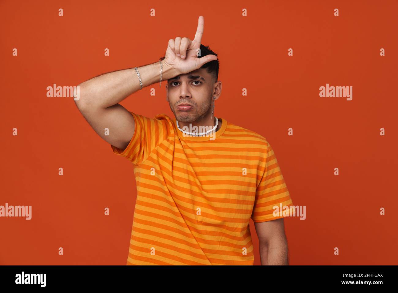 Young handsome stylish sad man with pursed lips doing loser gesture wit ...