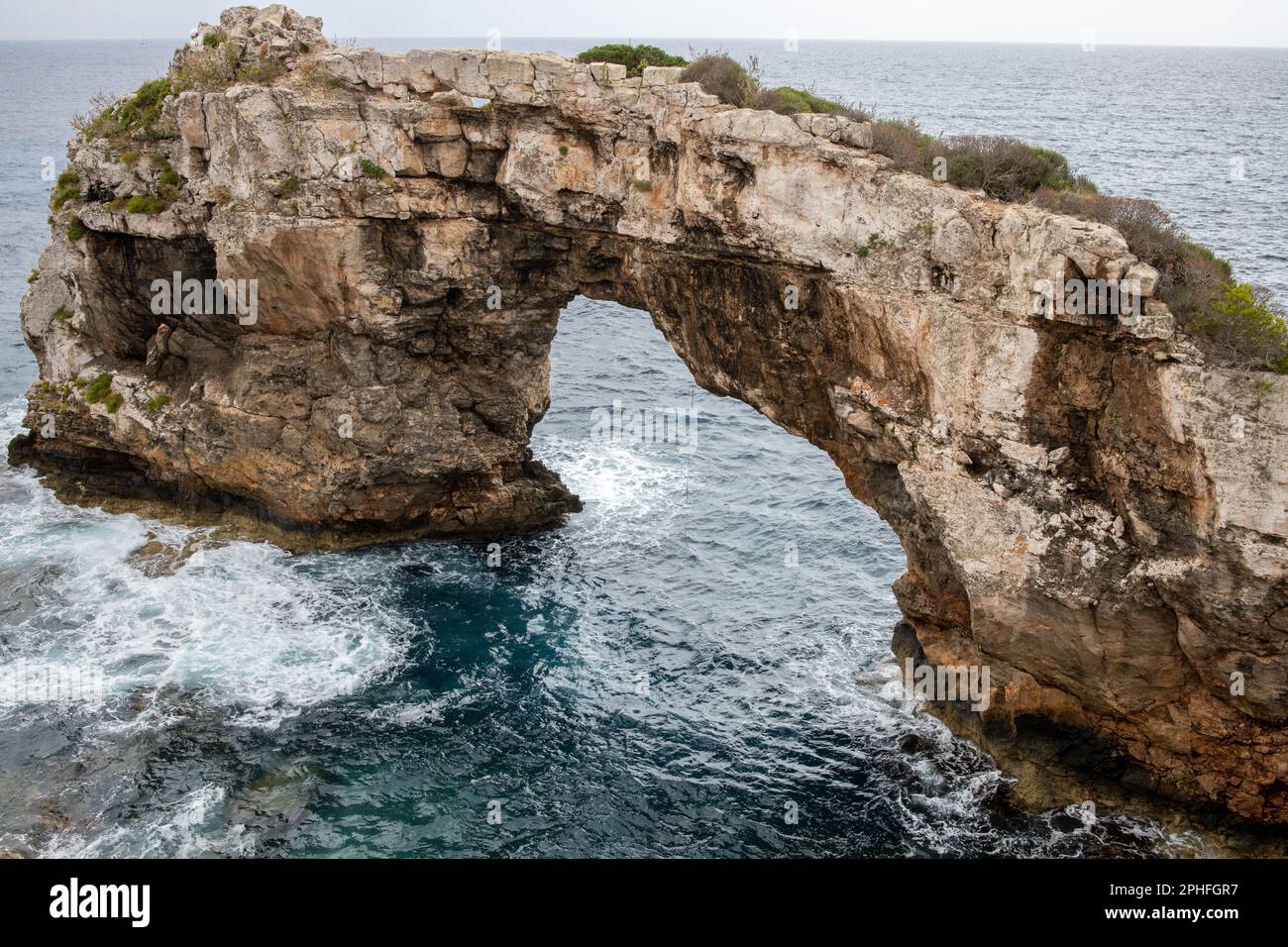 Aerial view of a majestic natural arch over the ocean, with towering ...