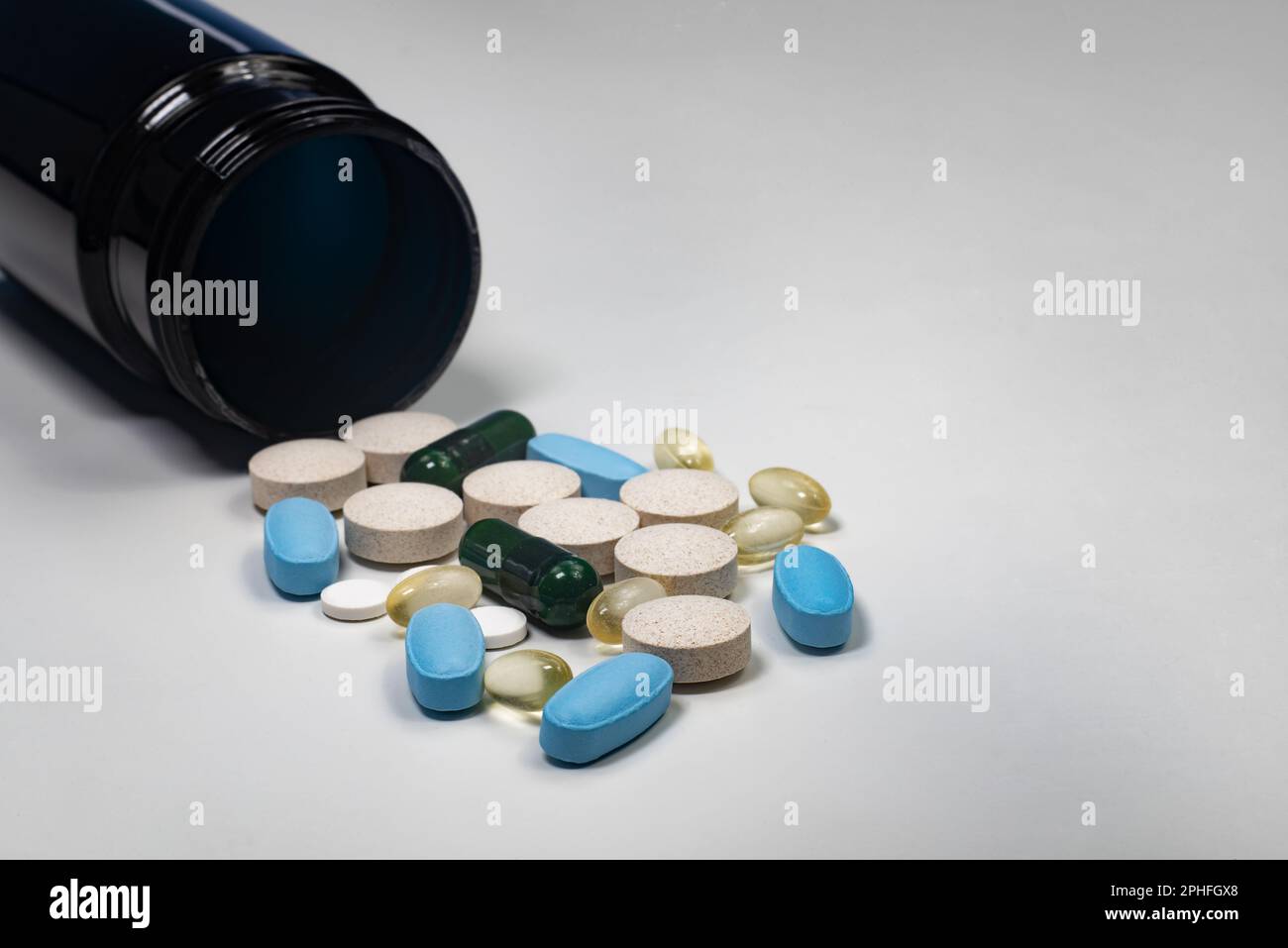 A pill bottle filled with assorted prescription tablets resting ...