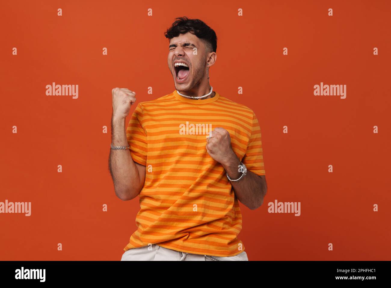 Brunette young man screaming while making winner gesture isolated over ...