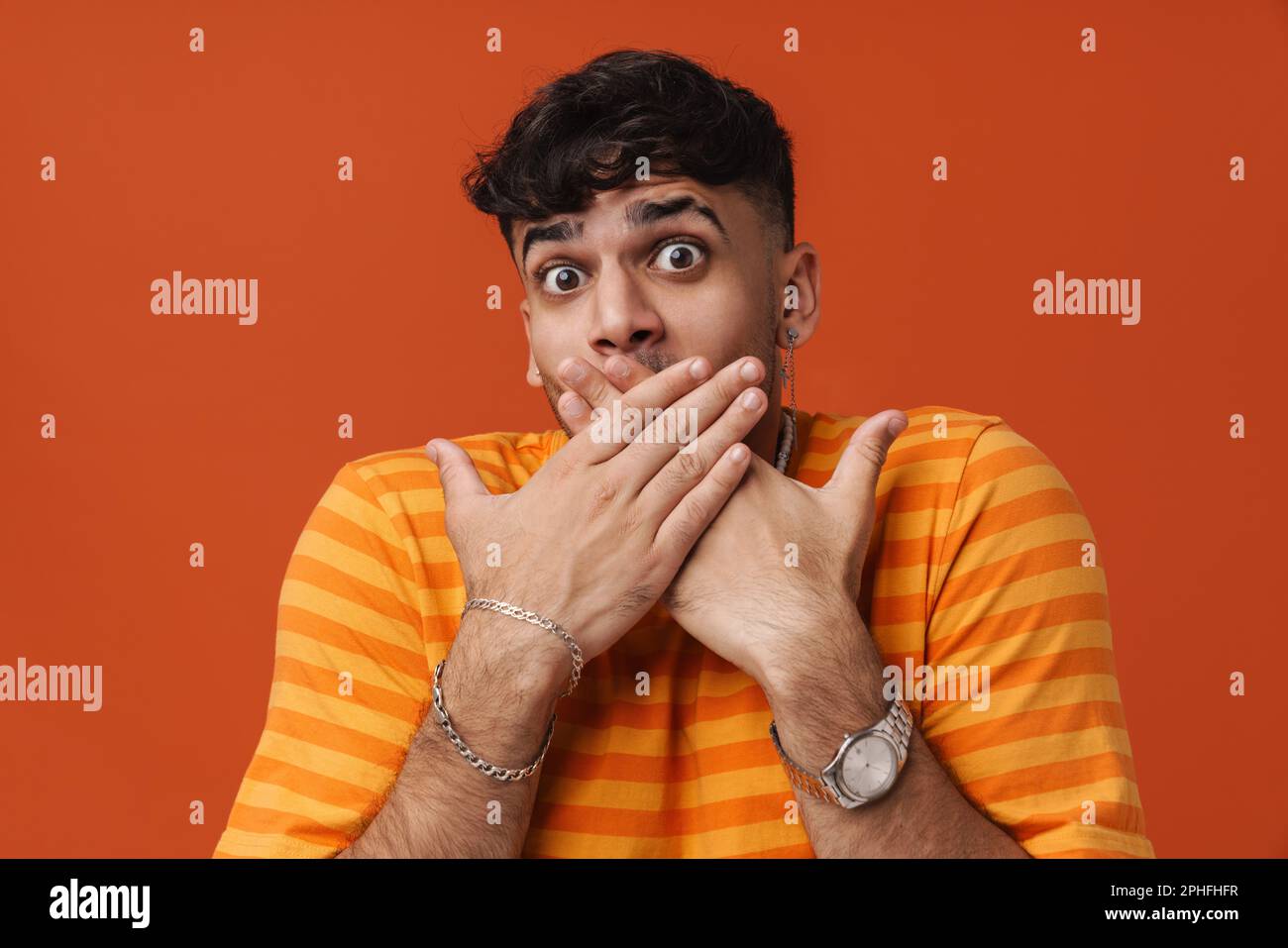 Brunette young man expressing surprise while covering his mouth ...