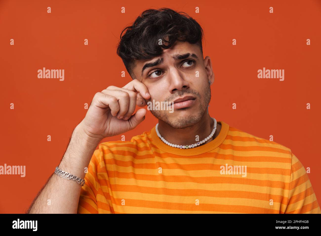 Brunette sad man wearing t-shirt wiping his tears while crying isolated ...