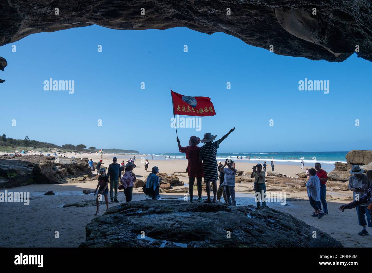 Silhouetted tourists and sightseers pose with a flag as they explore ...