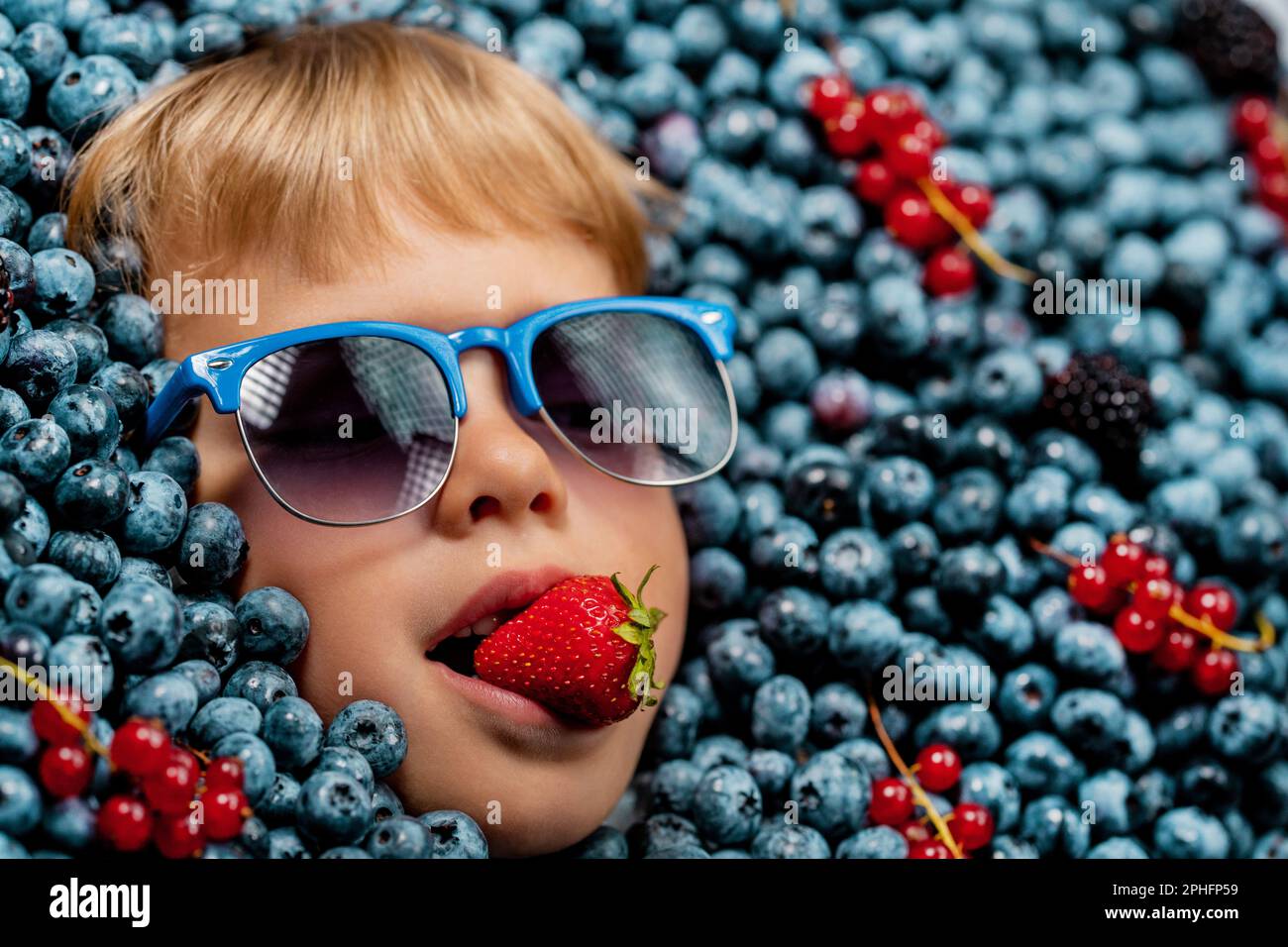 Little boy face in berries blueberries with strawberry, organic ...