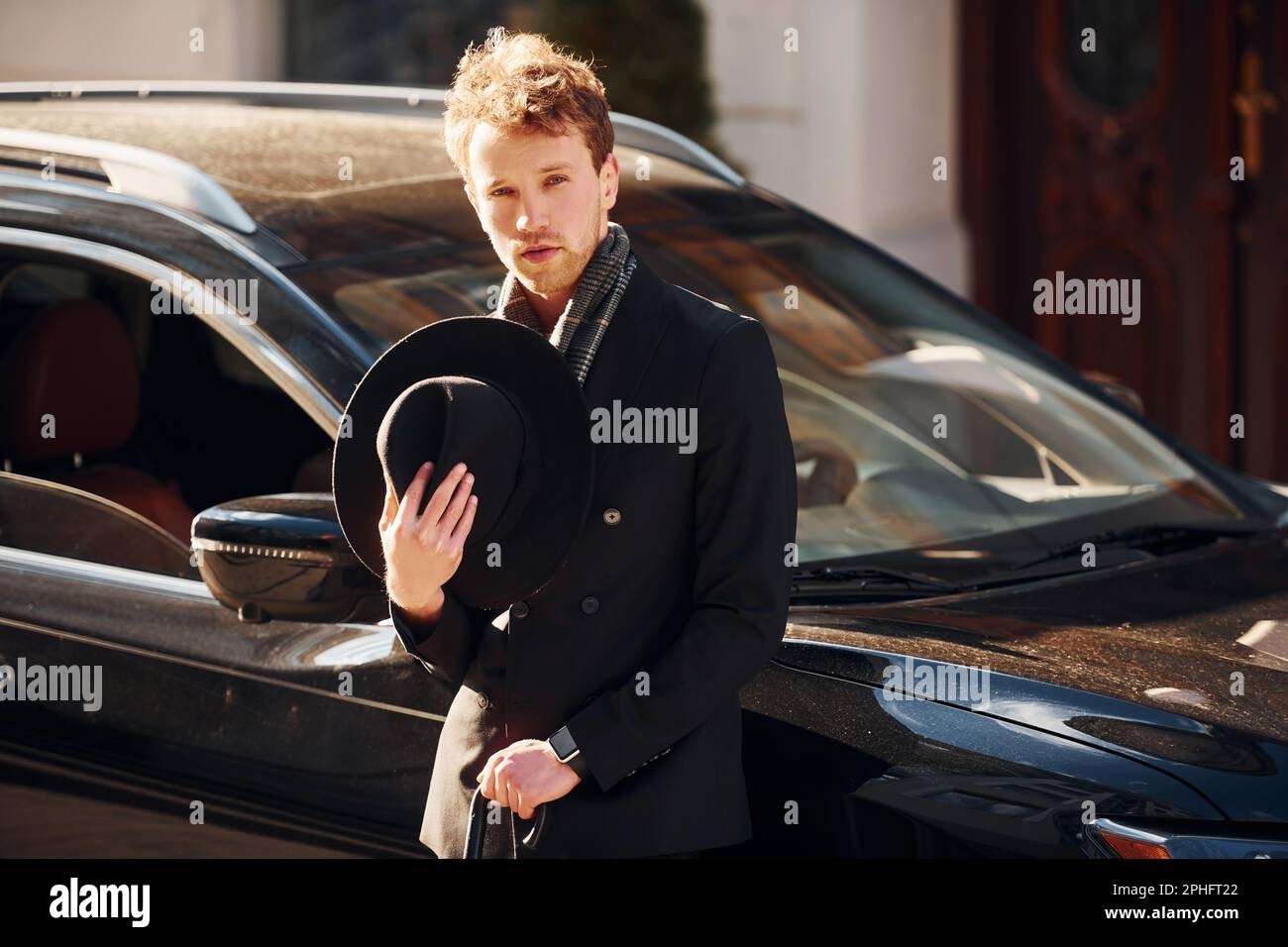 Standing near black car. Elegant young man in formal classy clothes ...