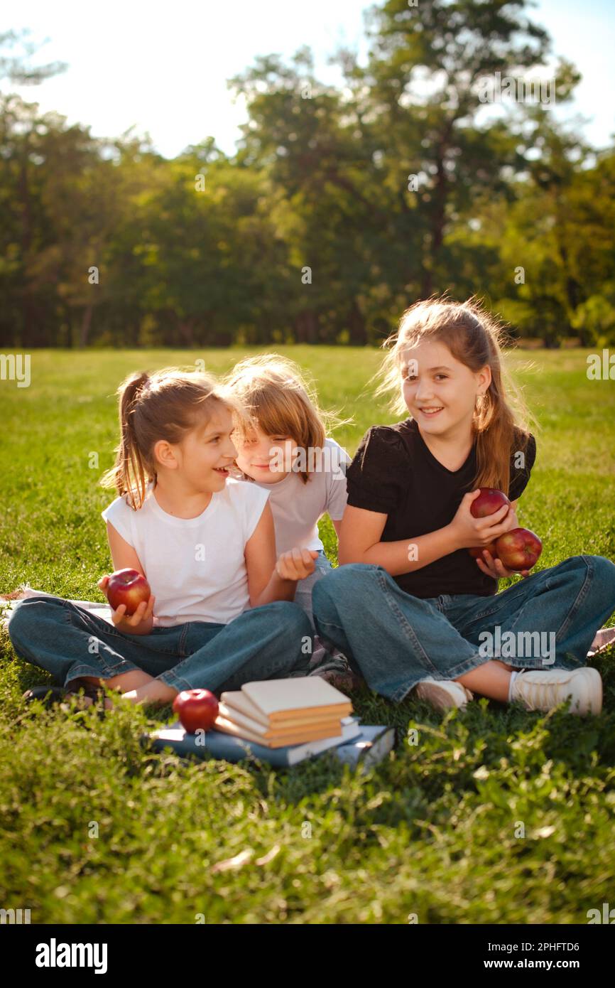 happy children play and have break in park sitting on green grass after ...