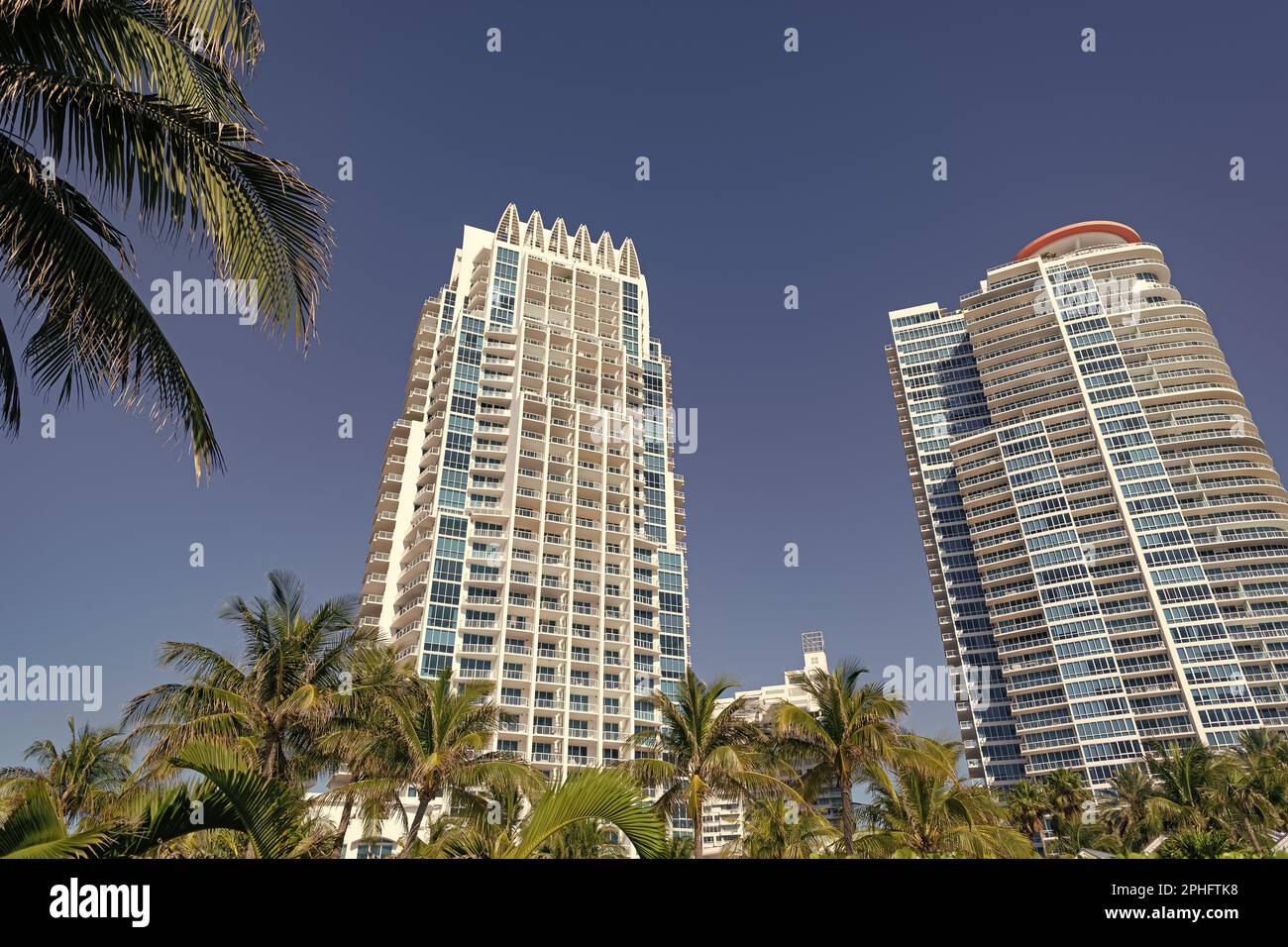 High-rise buildings modern urban architecture and palms on blue sky in ...