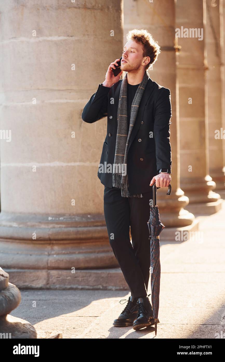 Elegant young man in formal classy clothes standing and talking by the ...