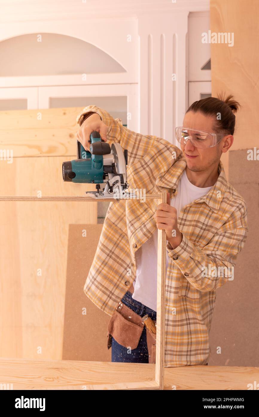 Craftsman with circular saw fixing furniture. Male woodworker in safety ...