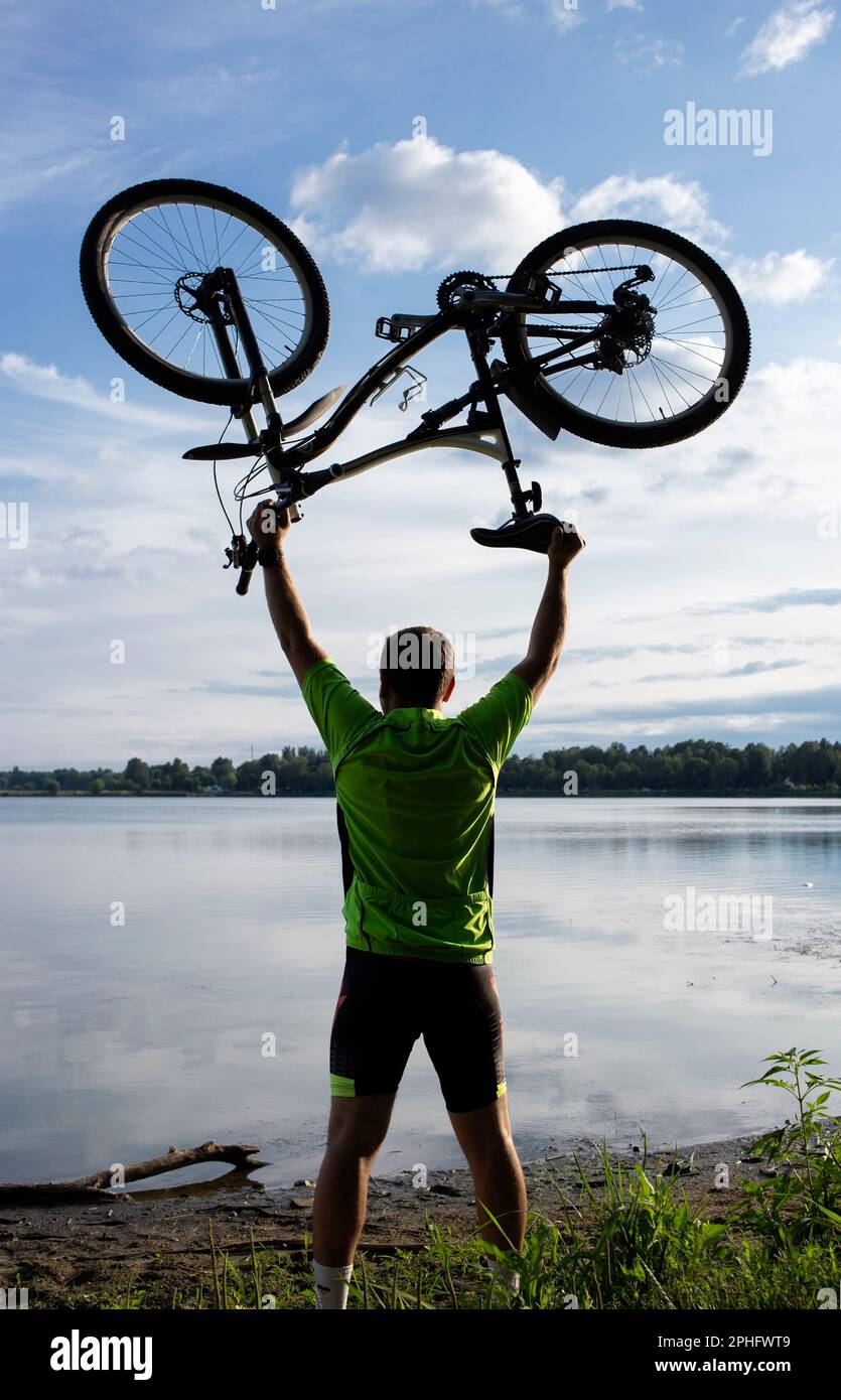 silhouette of unrecognizable adult man in bicycle uniform, raising ...