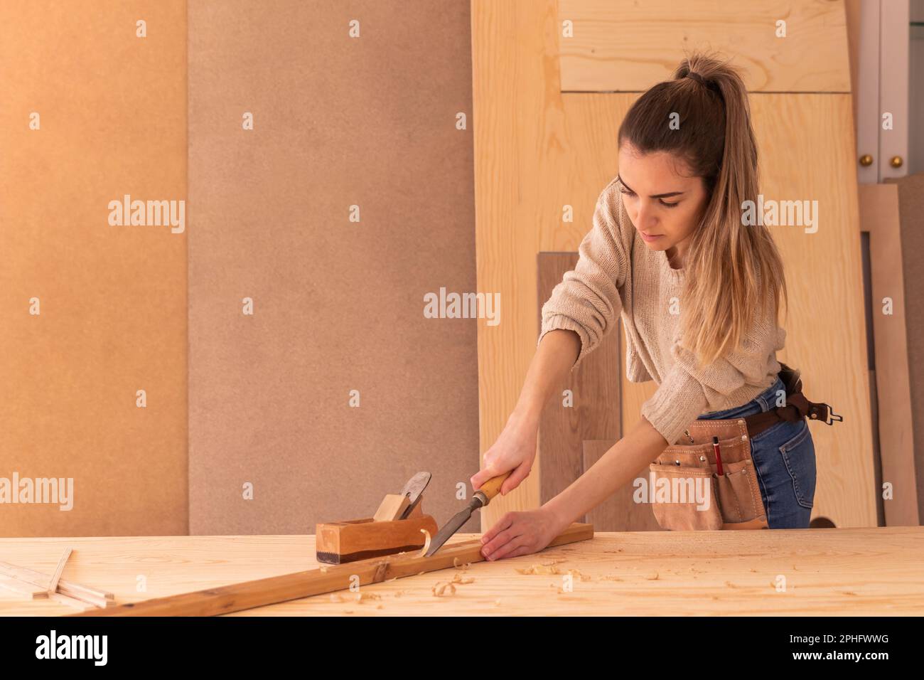 Craftswoman carving wood with chisel. Concentrated female joiner in ...