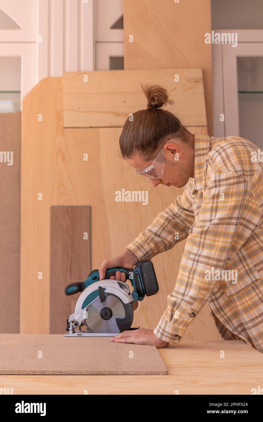 Handyman with circular saw working with wood. Side view of male ...