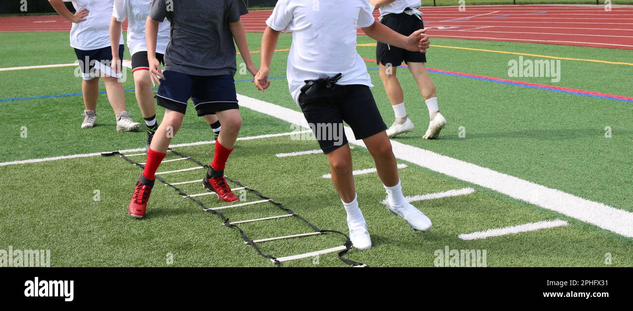 Young football players at summer training camp running in the ladder ...