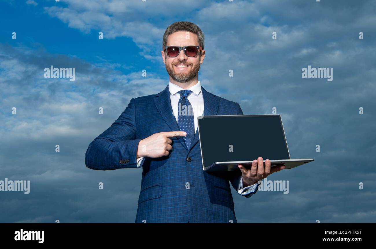 businessman presenting laptop wearing suit, point finger. photo of ...