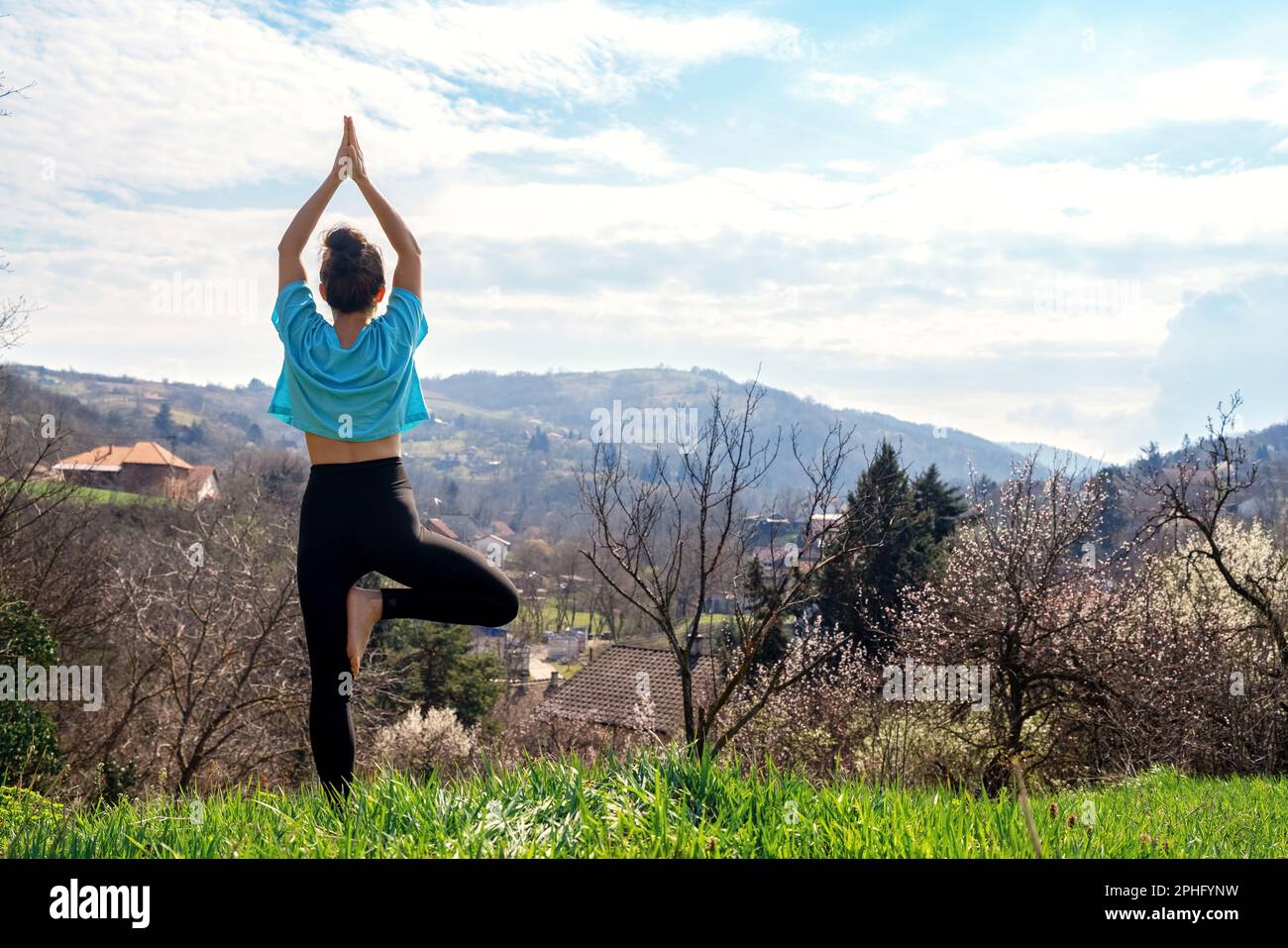Woman doing yoga exercise Vrikshasana Tree Pose in nature against ...