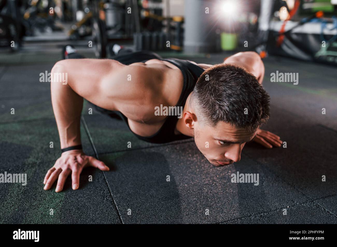 Doing push-ups. Young sportive strong man in black wear have workout ...