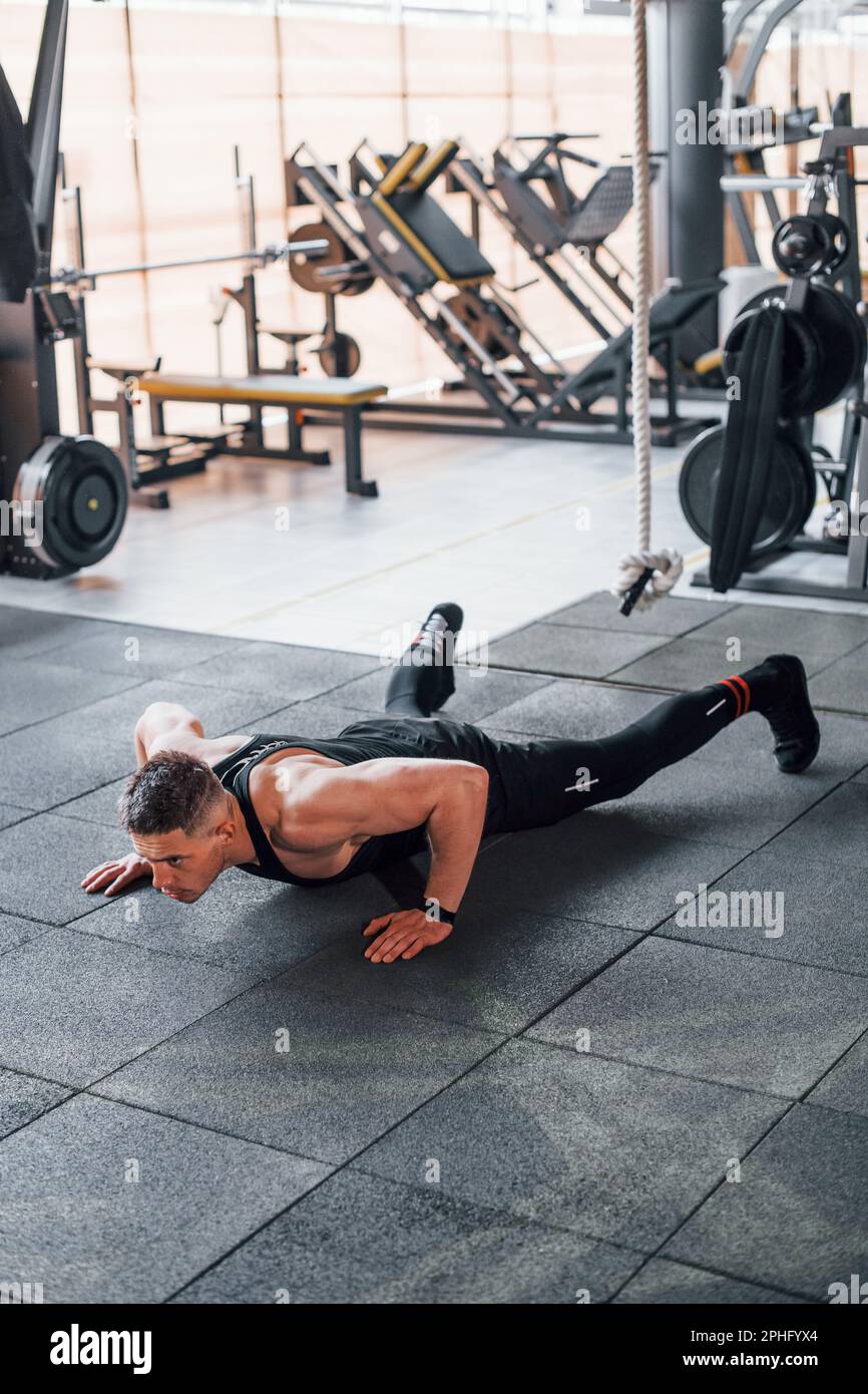 Doing push-ups. Young sportive strong man in black wear have workout ...