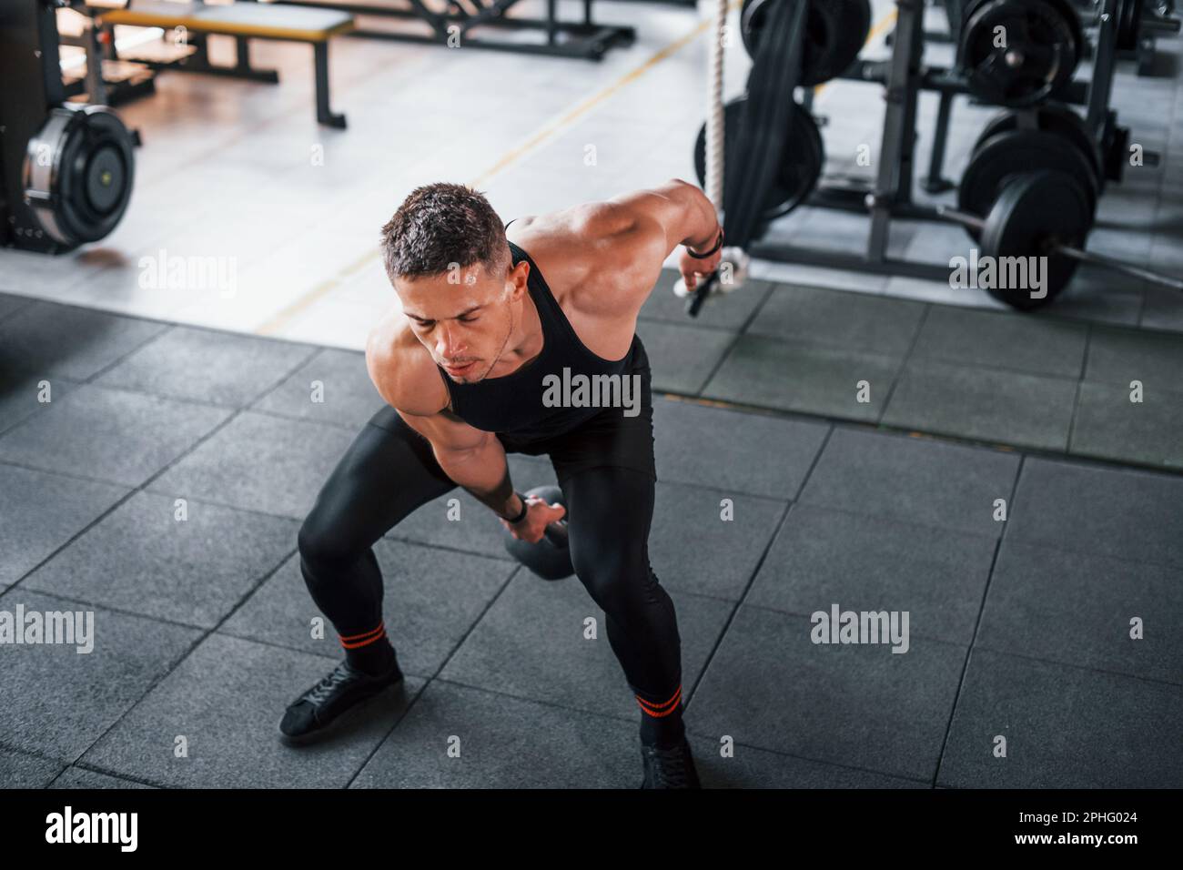 Liting weight. Young sportive strong man in black wear have workout day ...