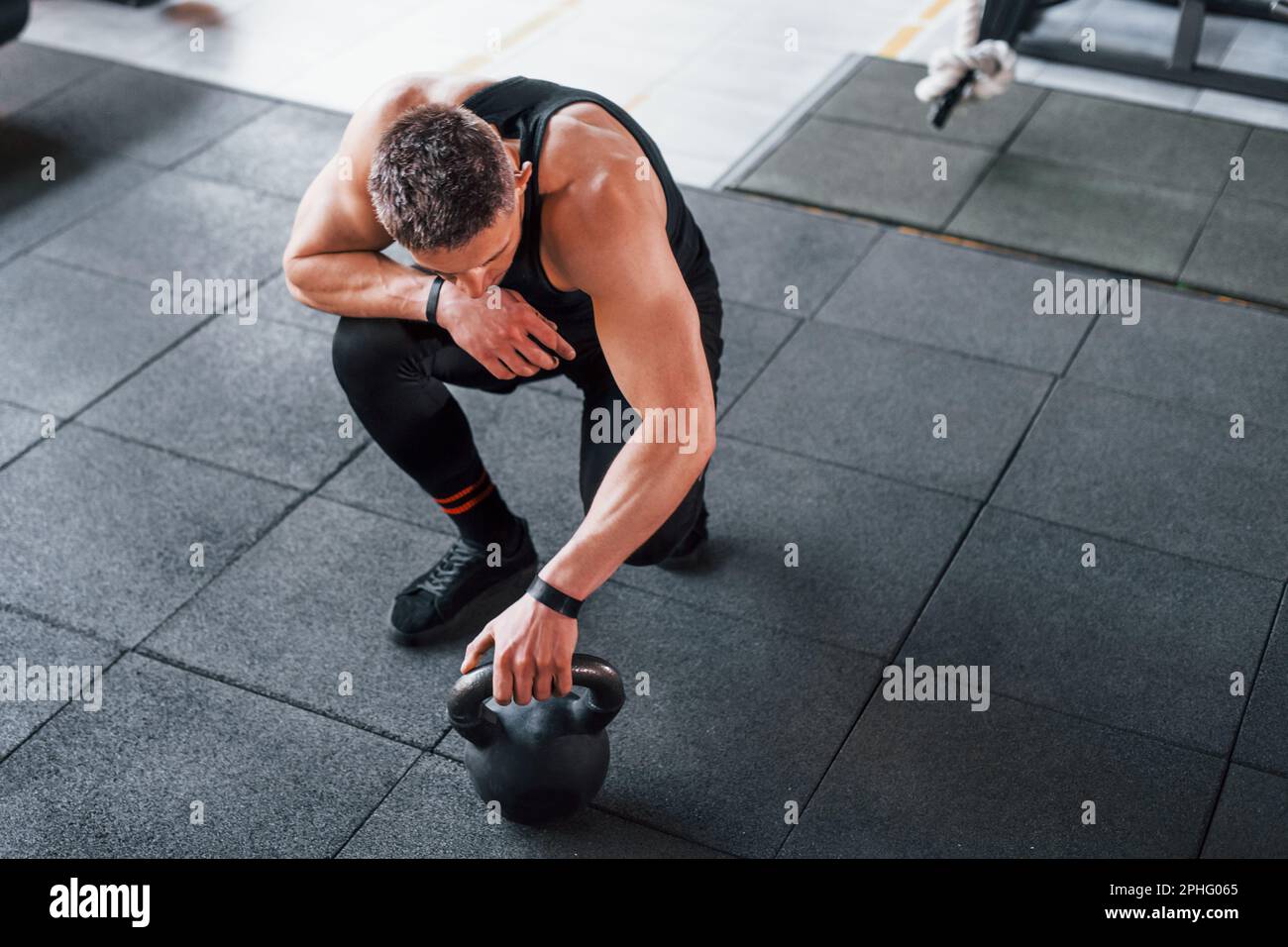 Liting weight. Young sportive strong man in black wear have workout day ...