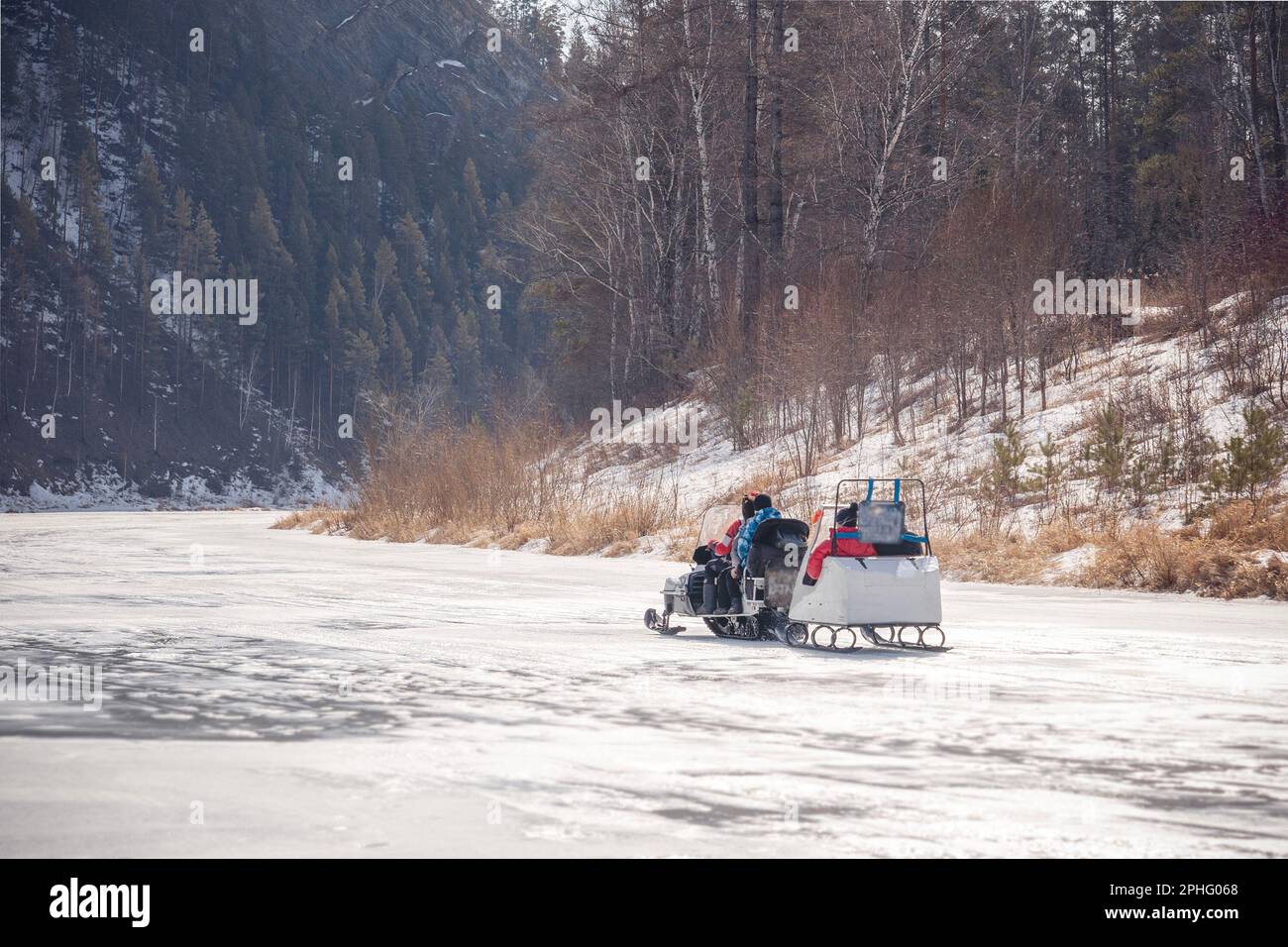 Winter walk with family on a snowmobile on a frozen river. A snowmobile ...