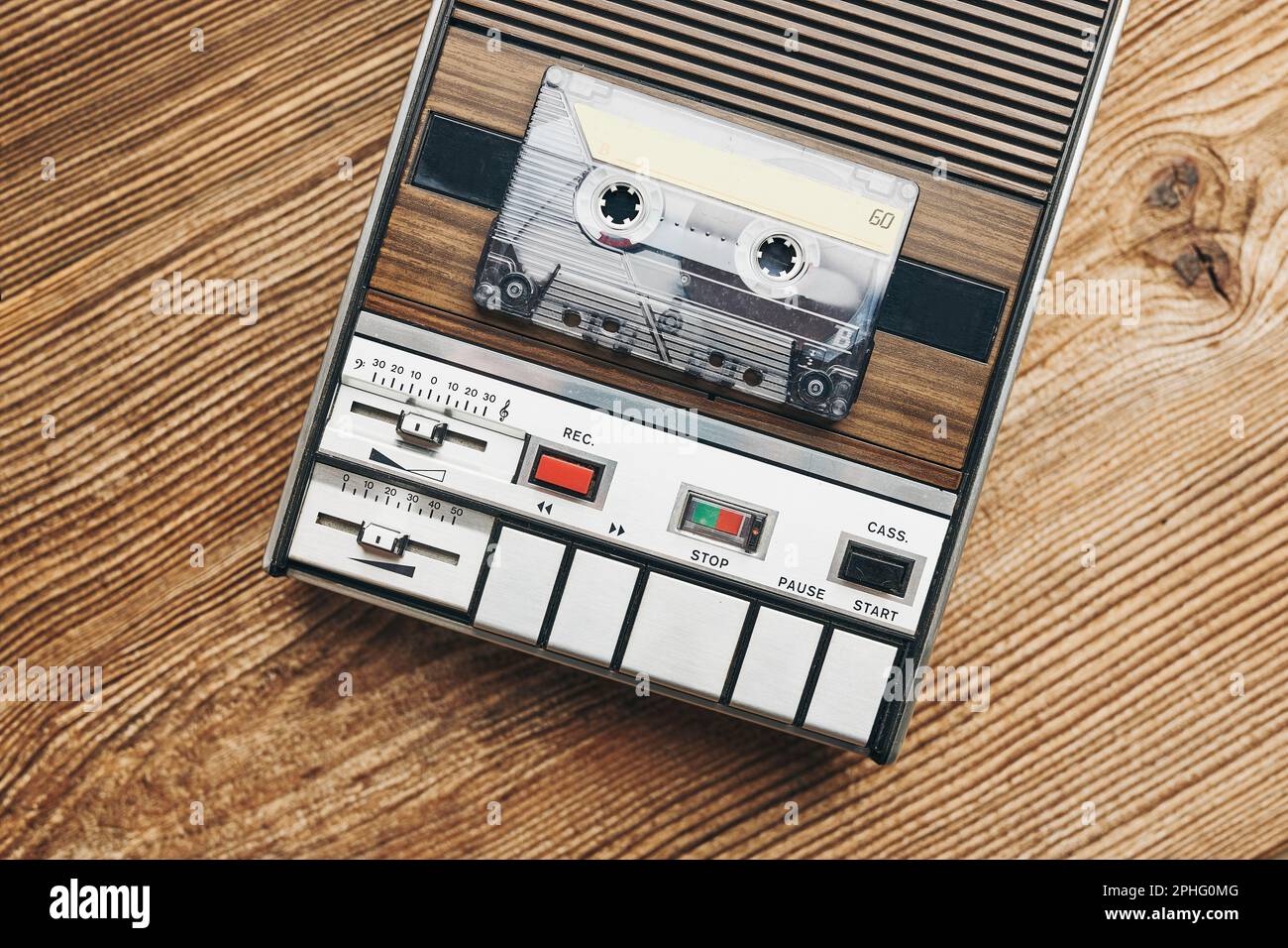 Compact cassette tapes and cassette recorder on wooden table. Retro ...