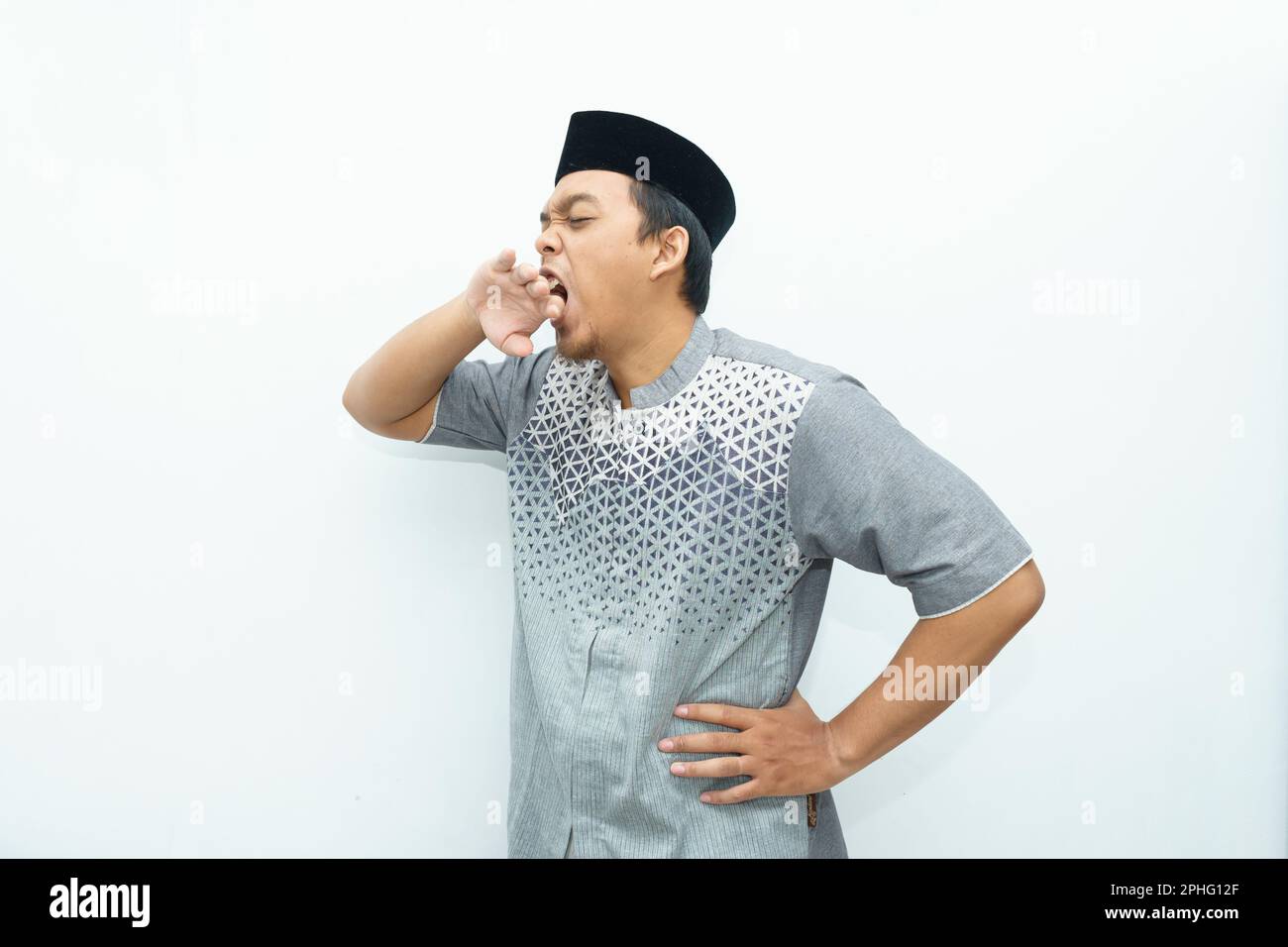 Portrait of Asian Indonesian Muslim man yawning sleepily and covering ...