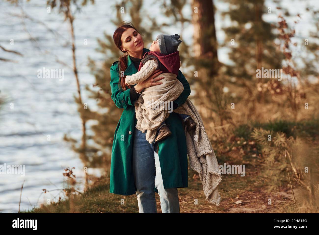 Mother with her little son have a walk in spring forest at daytime ...