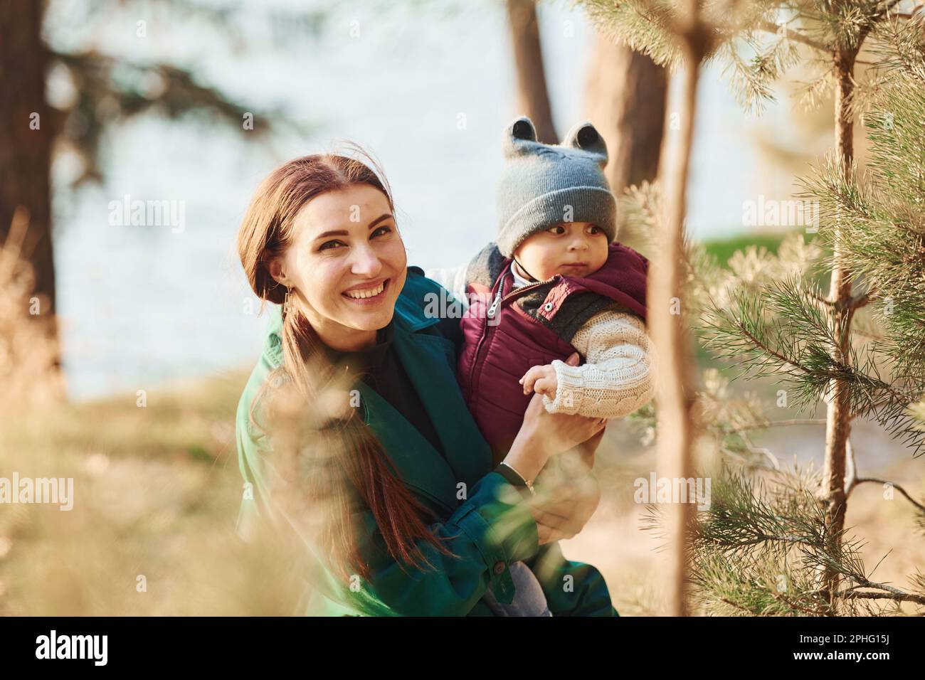 Mother with her little son have a walk in spring forest at daytime ...