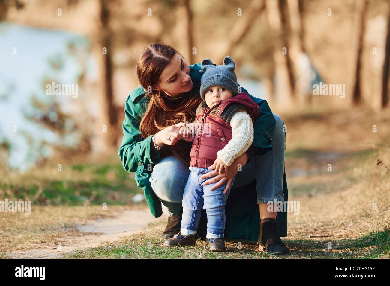 Mother with her little son have a walk in spring forest at daytime ...