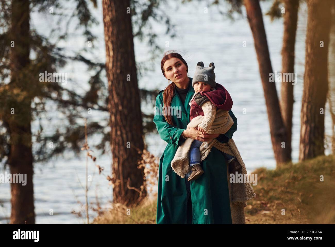 Mother with her little son have a walk in spring forest at daytime ...